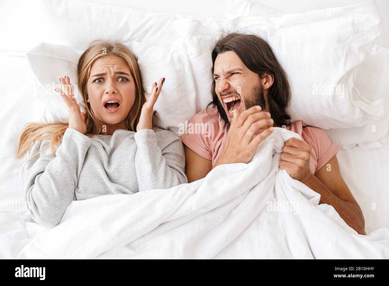 Beautiful angry young couple laying in bed at home, having a big ...