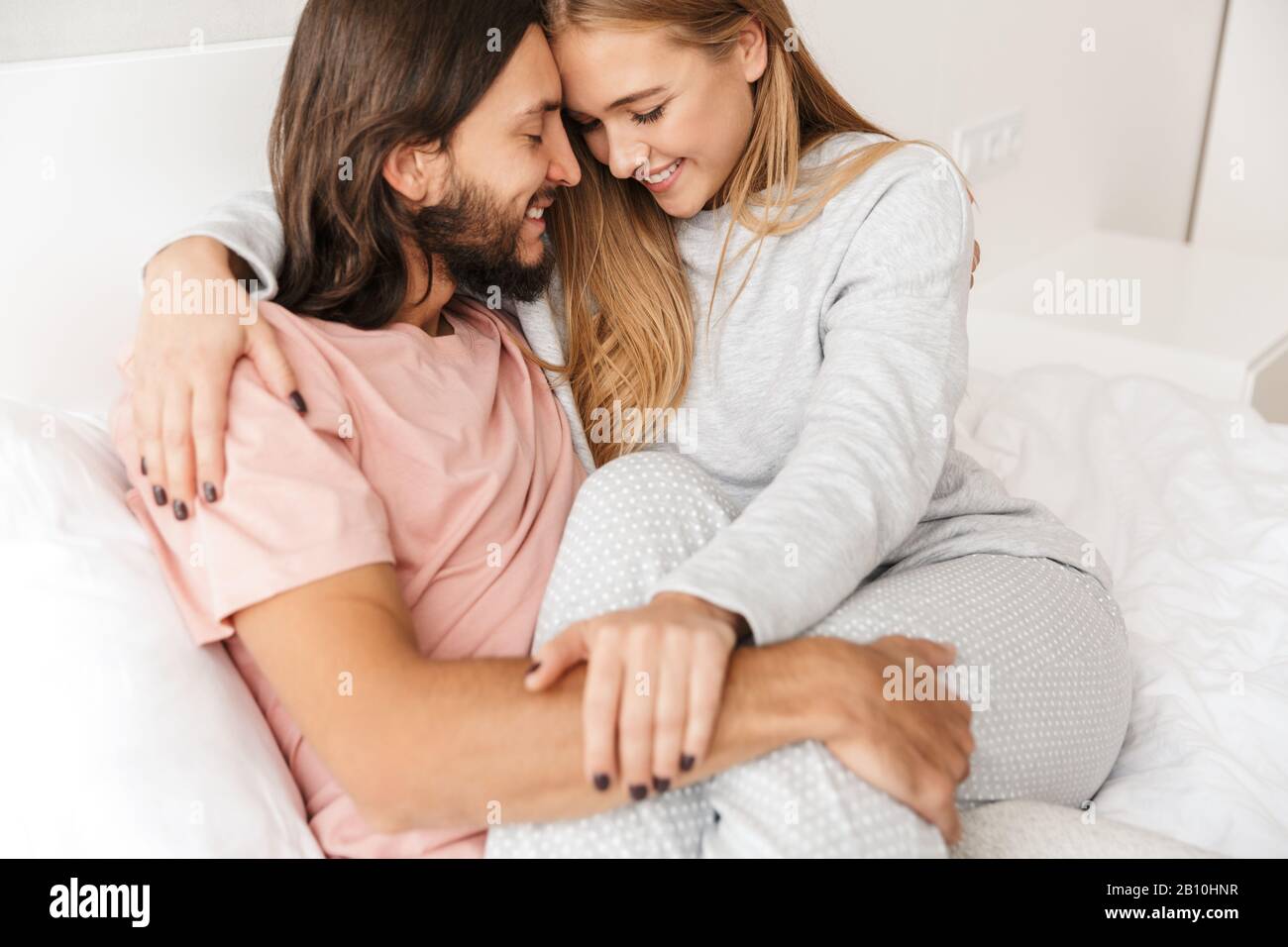 Photo of cute happy positive young loving couple in bed hugging indoors at home Stock Photo - Alamy