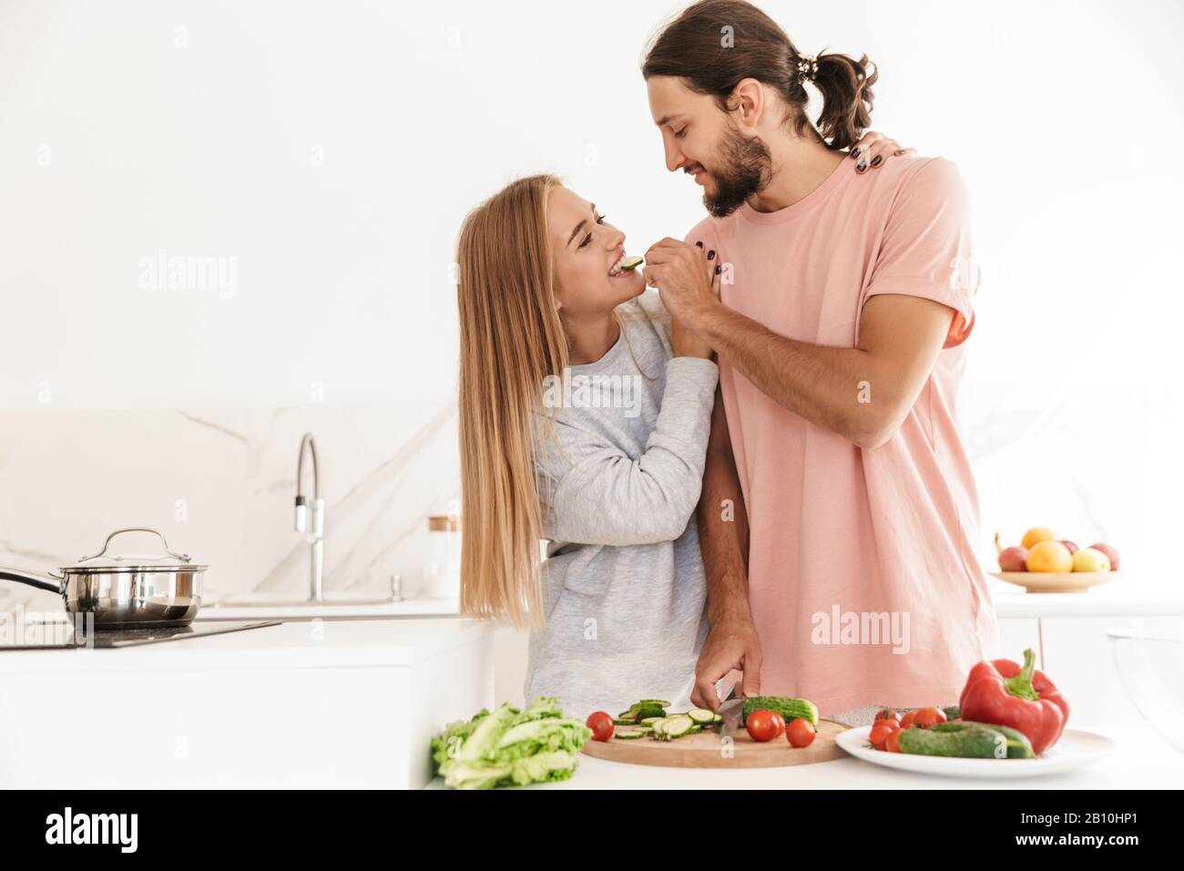 Cheerful lovely couple cooking healthy meal together while standing at ...