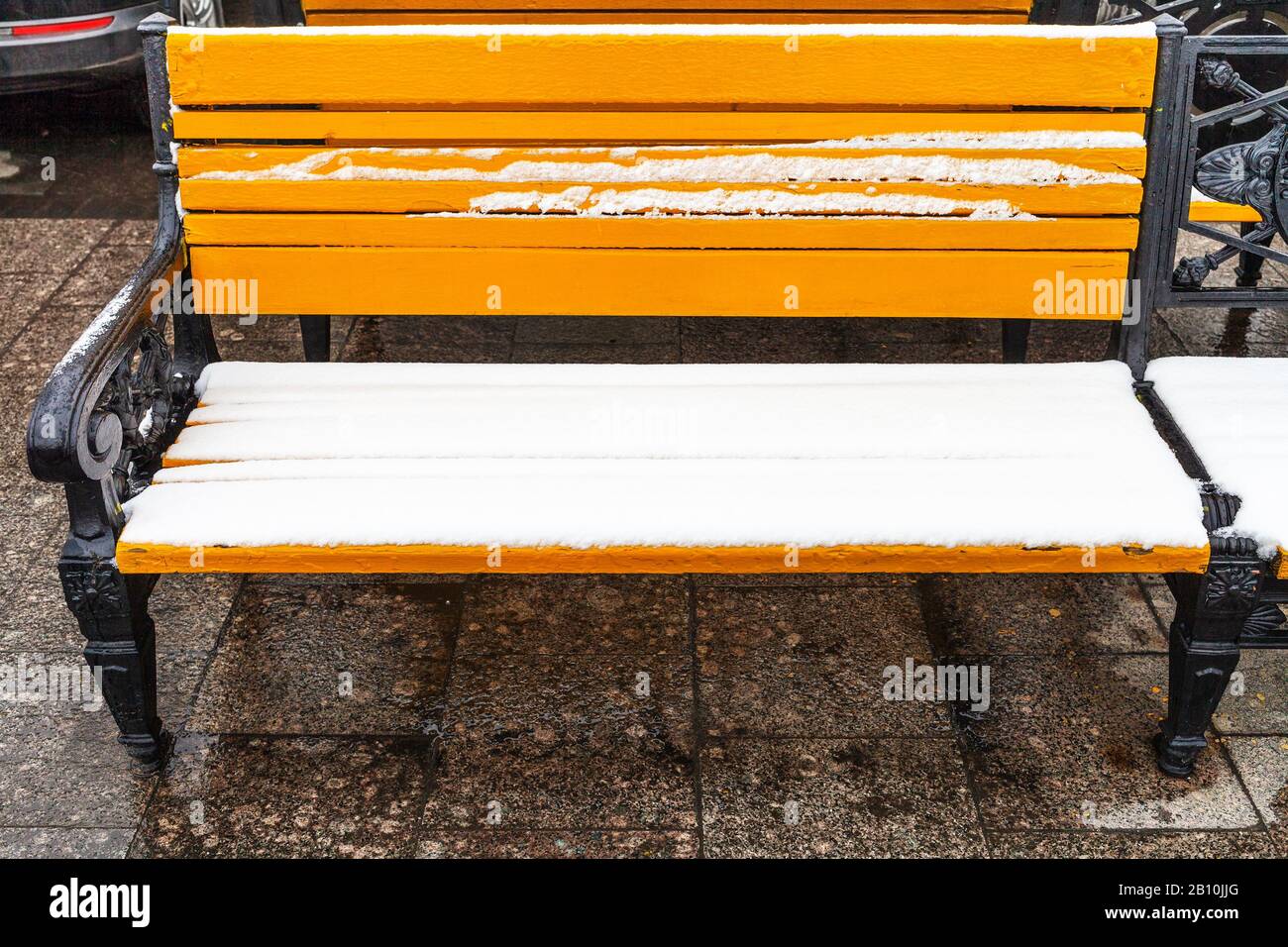 front view of yellow wooden bench covered by snow on Manezhnaya square ...