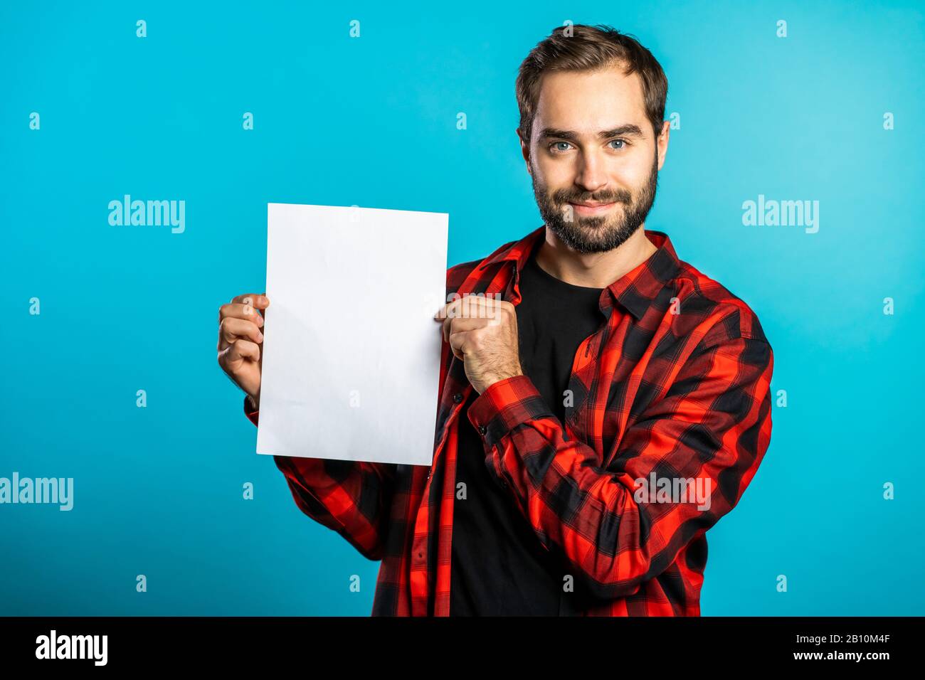 Handsome man holding vertical white a4 paper poster. Copy space ...