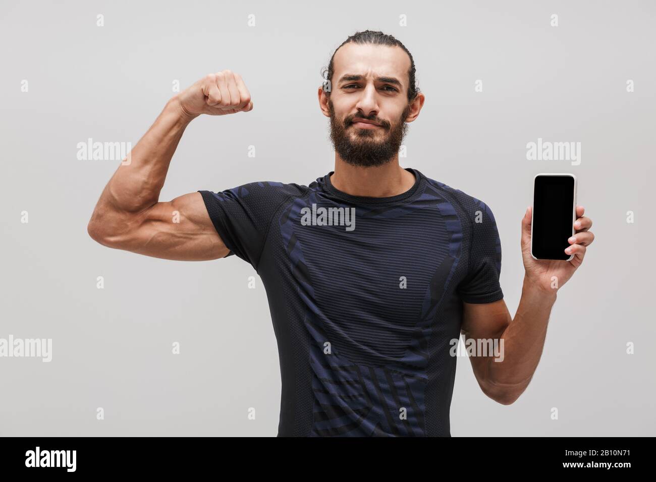 Image of bearded muscular sportsman wearing tracksuit showing his bicep ...