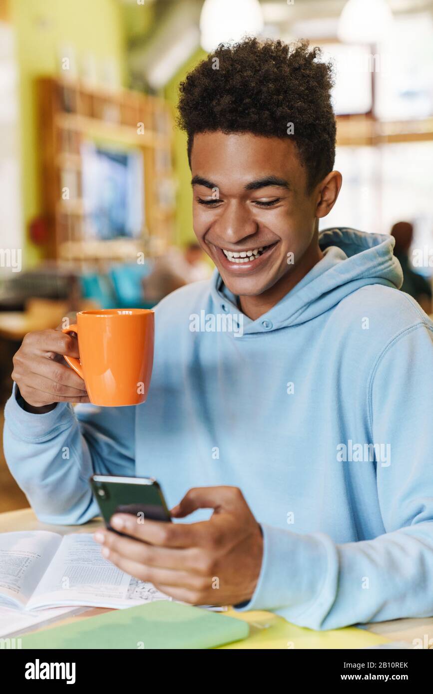 Smiling african boy teenager studying while sitting at the hub indoors ...