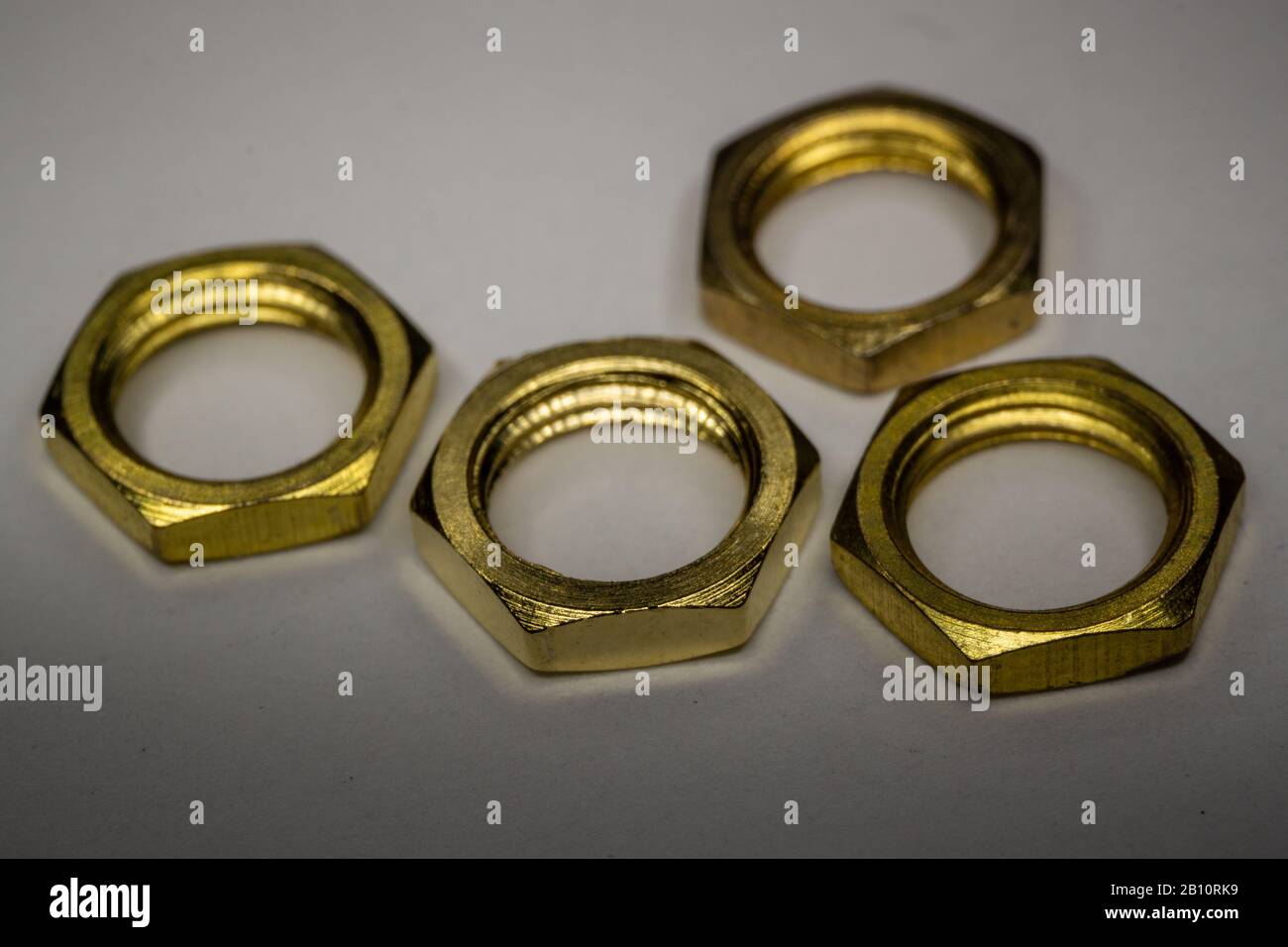 High detail close-up macro of four arranged gold screw nuts isolated on ...