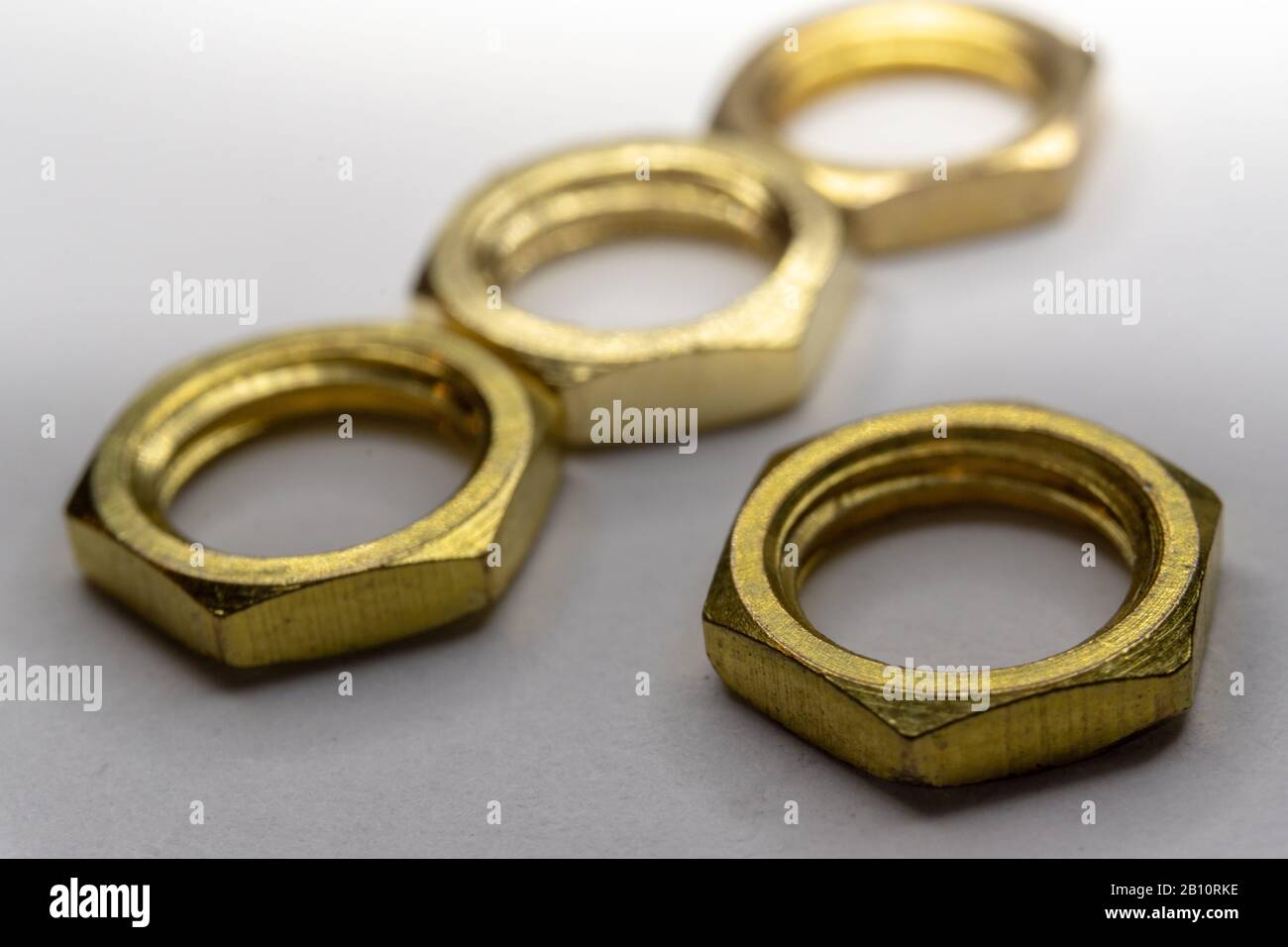 High detail close-up macro of four arranged gold screw nuts isolated on ...