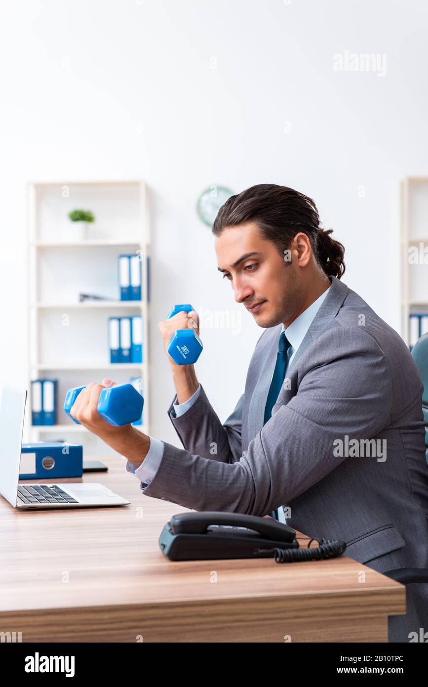 The young handsome employee doing sport exercises at workplace Stock ...