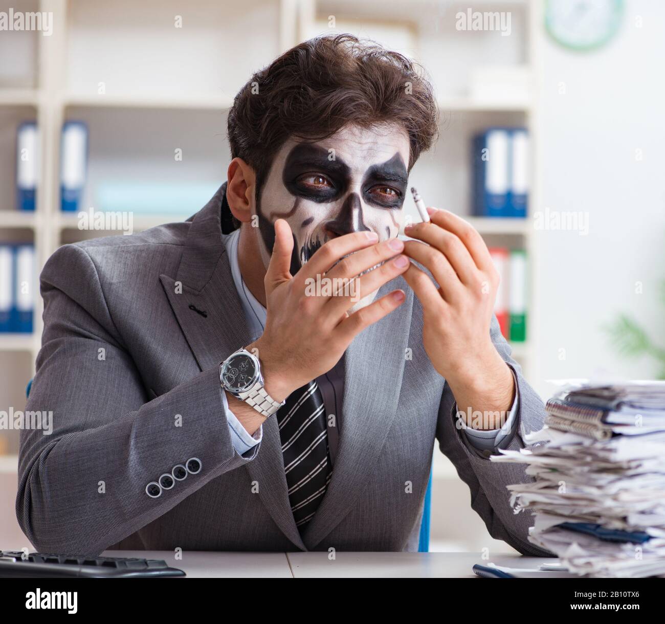 Businessman with scary face mask working in office Stock Photo - Alamy