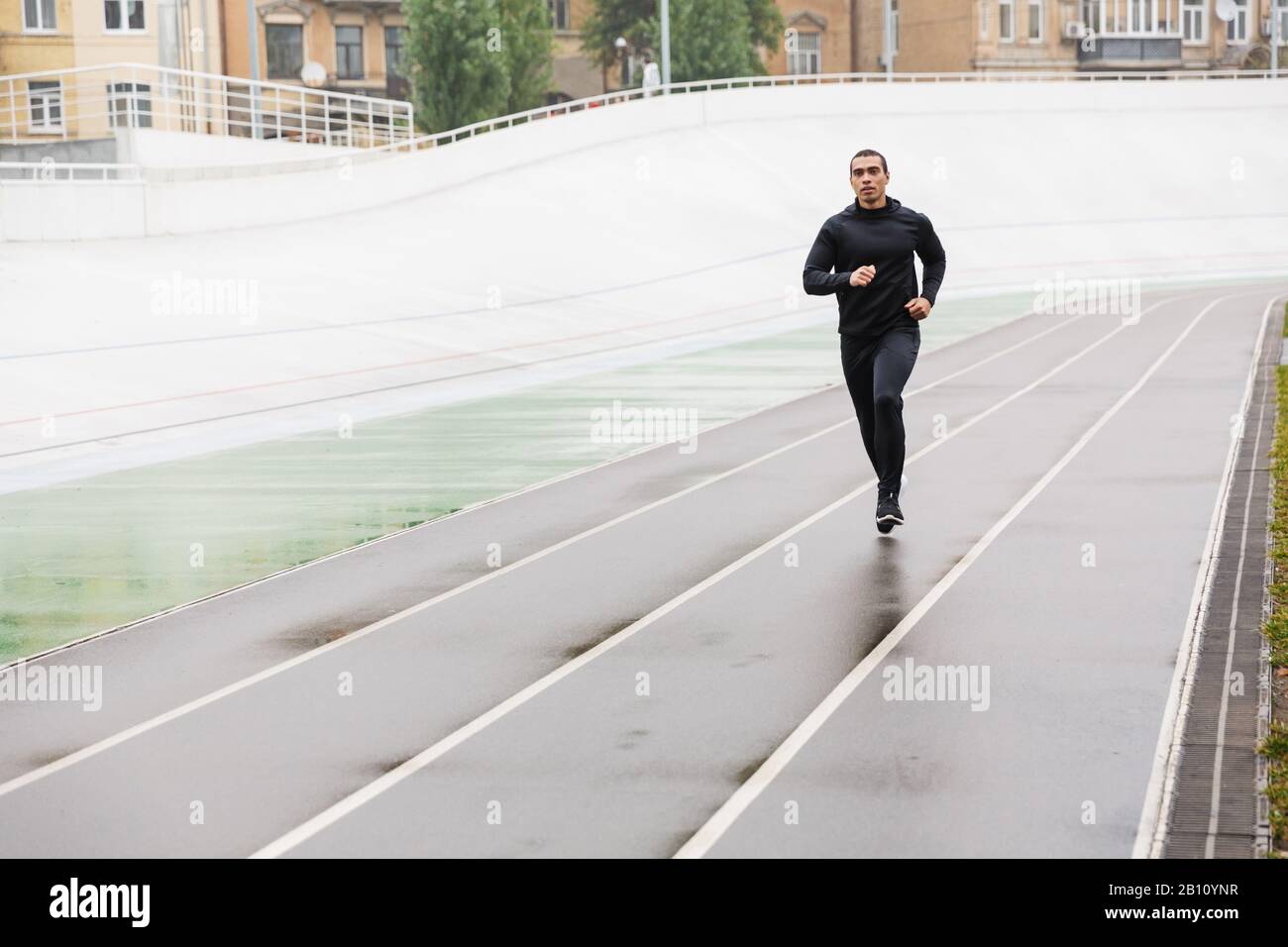 Photo of athletic strong sportsman in tracksuit running while working ...