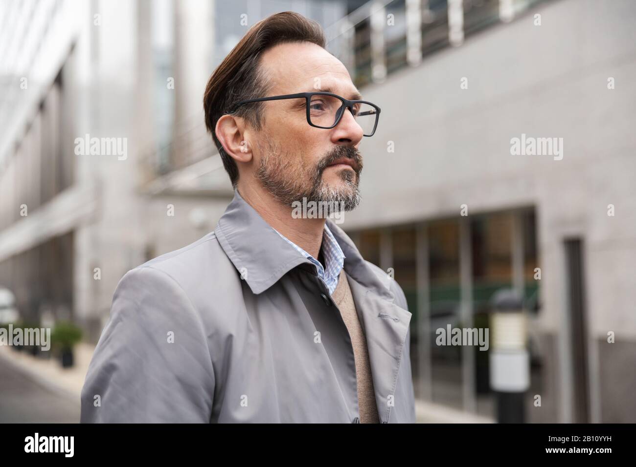 Image of mature businessman in eyeglasses looking forward while ...