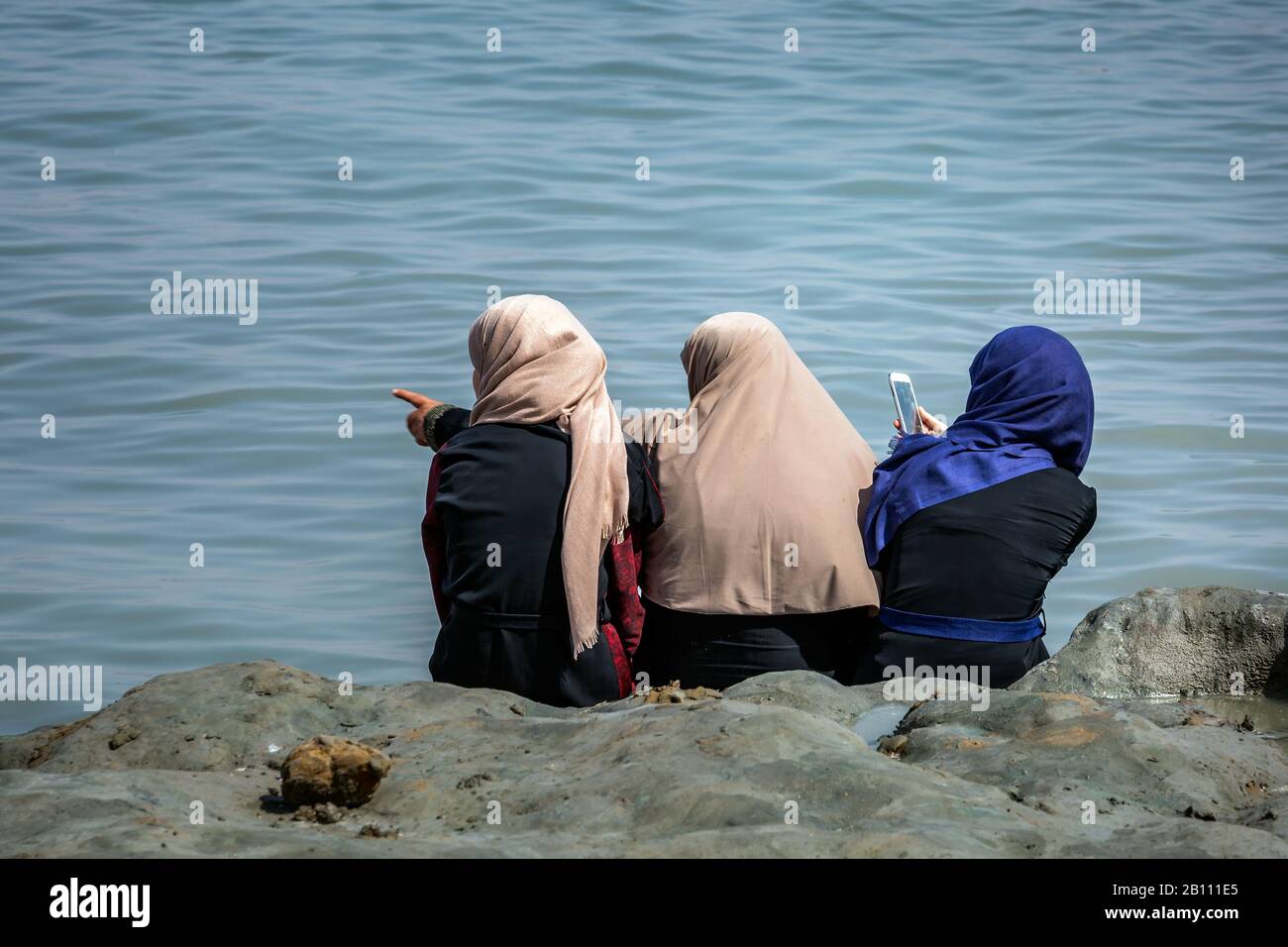 Muslim women fully covered with clothes on the beach. Body care ...