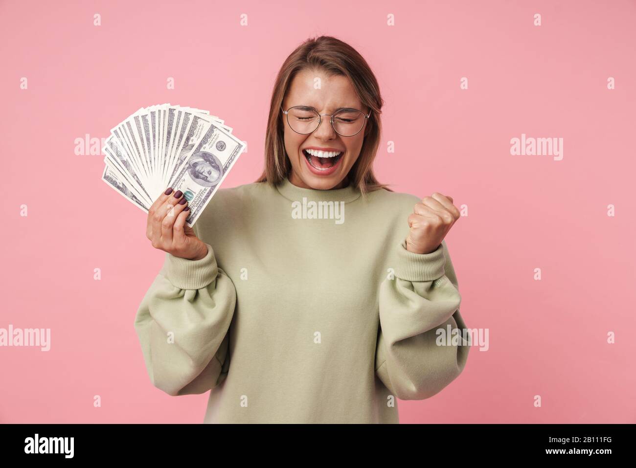 Portrait of nice excited woman in eyeglasses holding banknotes while ...
