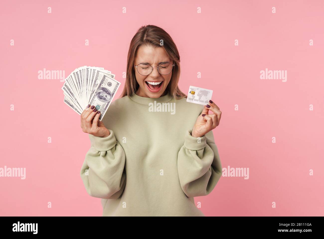 Portrait of nice excited woman in eyeglasses holding banknotes and ...