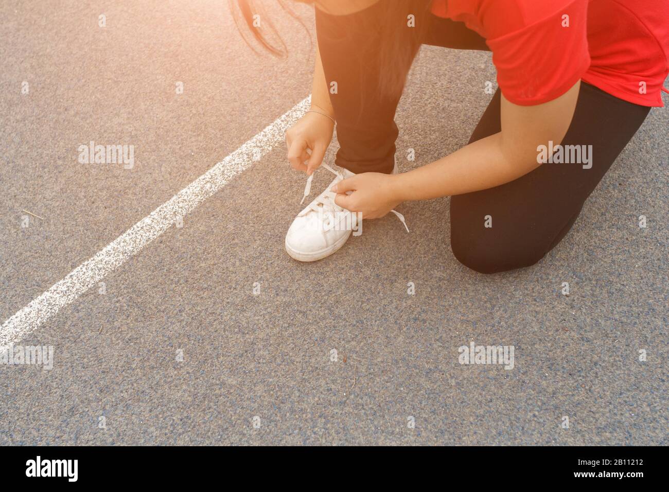 Close-up of sportgirl tying sneakers on running shoes before practice ...