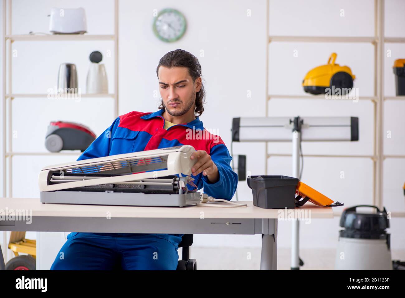 The young male contractor repairing air-conditioner at workshop Stock ...