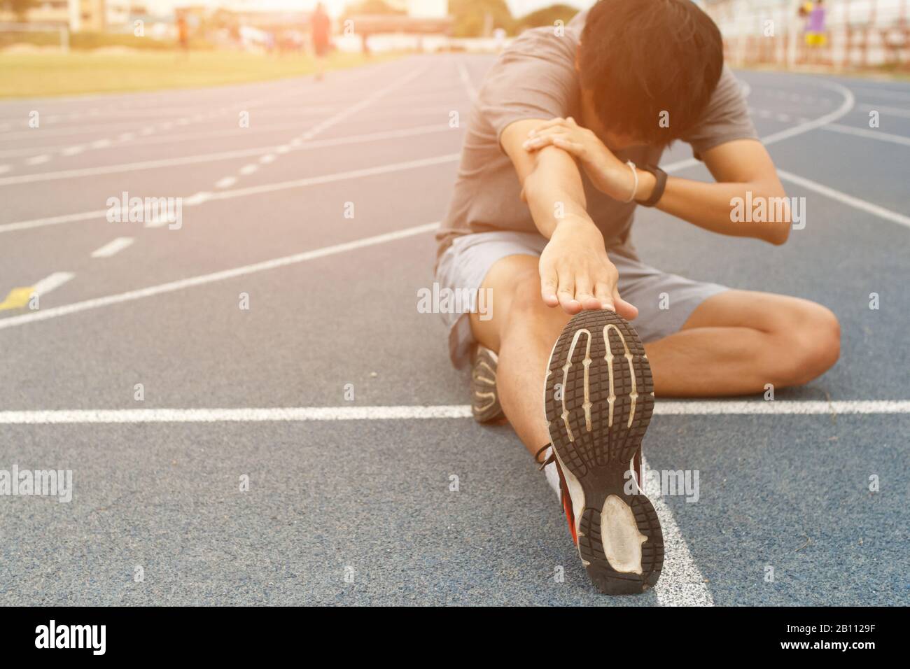 Young man runner stretching legs before run - workout concept Stock ...