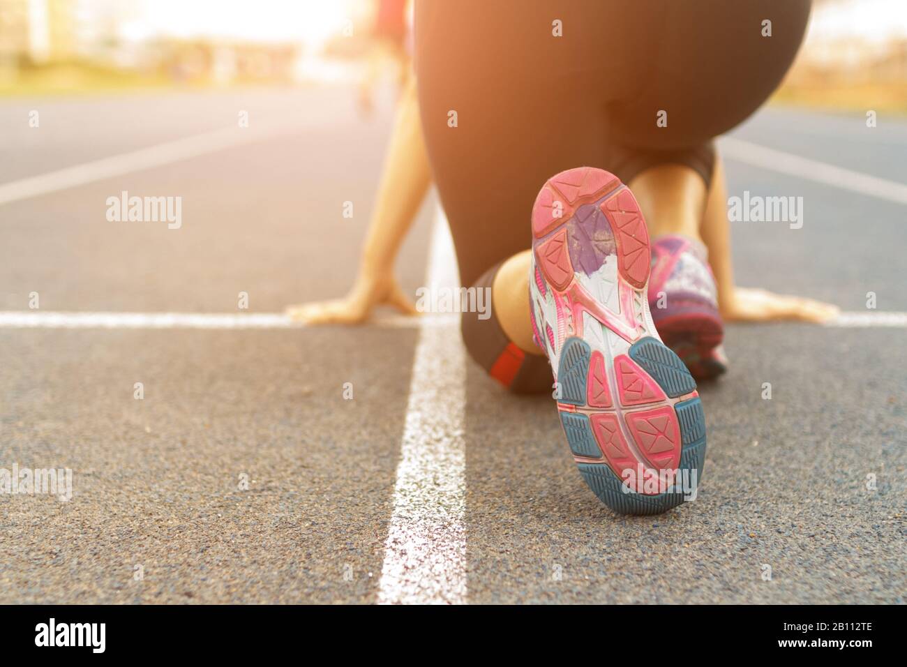 woman in running start pose on the blue running track in stadium Stock ...