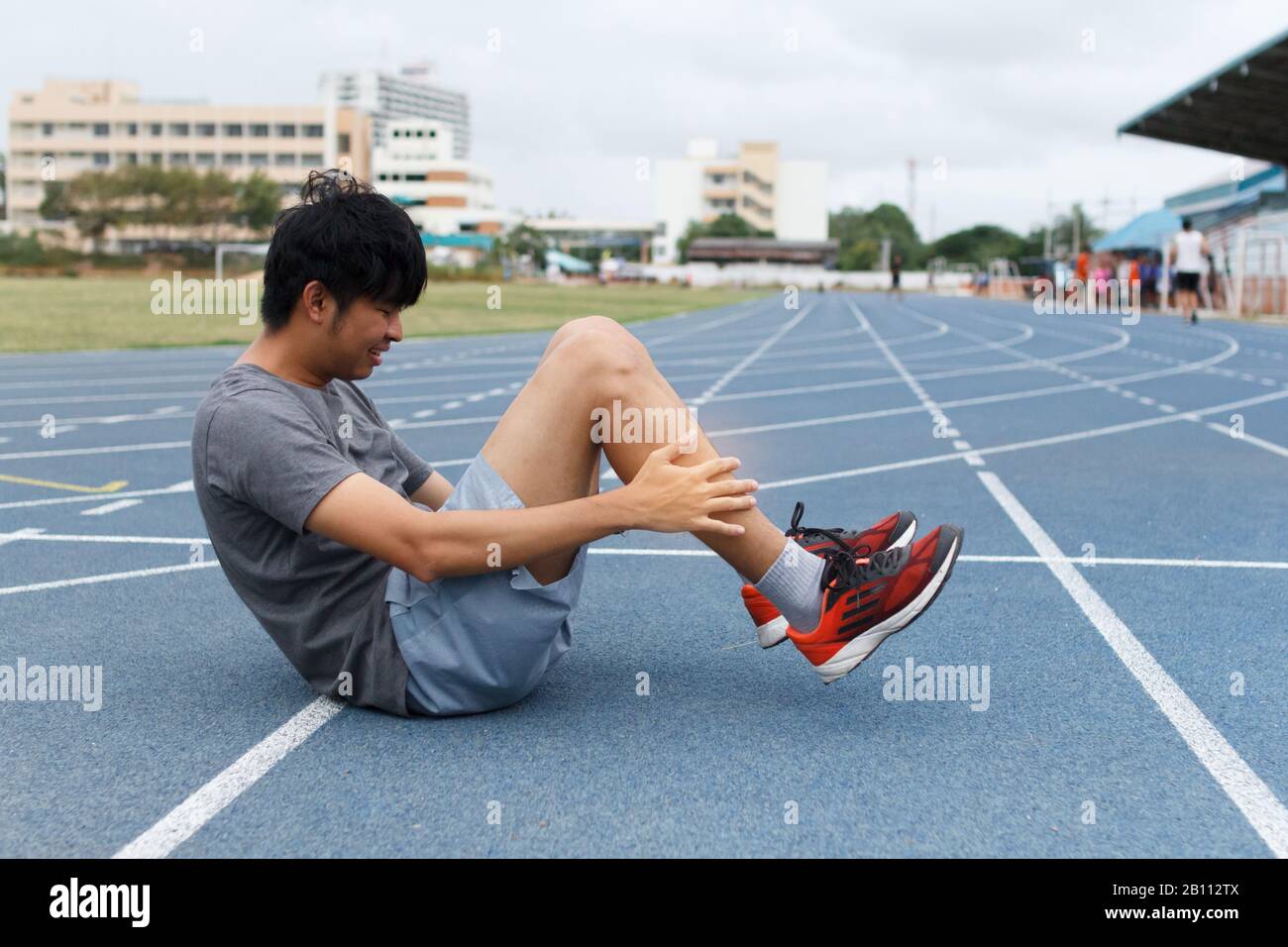 The asian man use hands hold on his leg after running on the blue ...