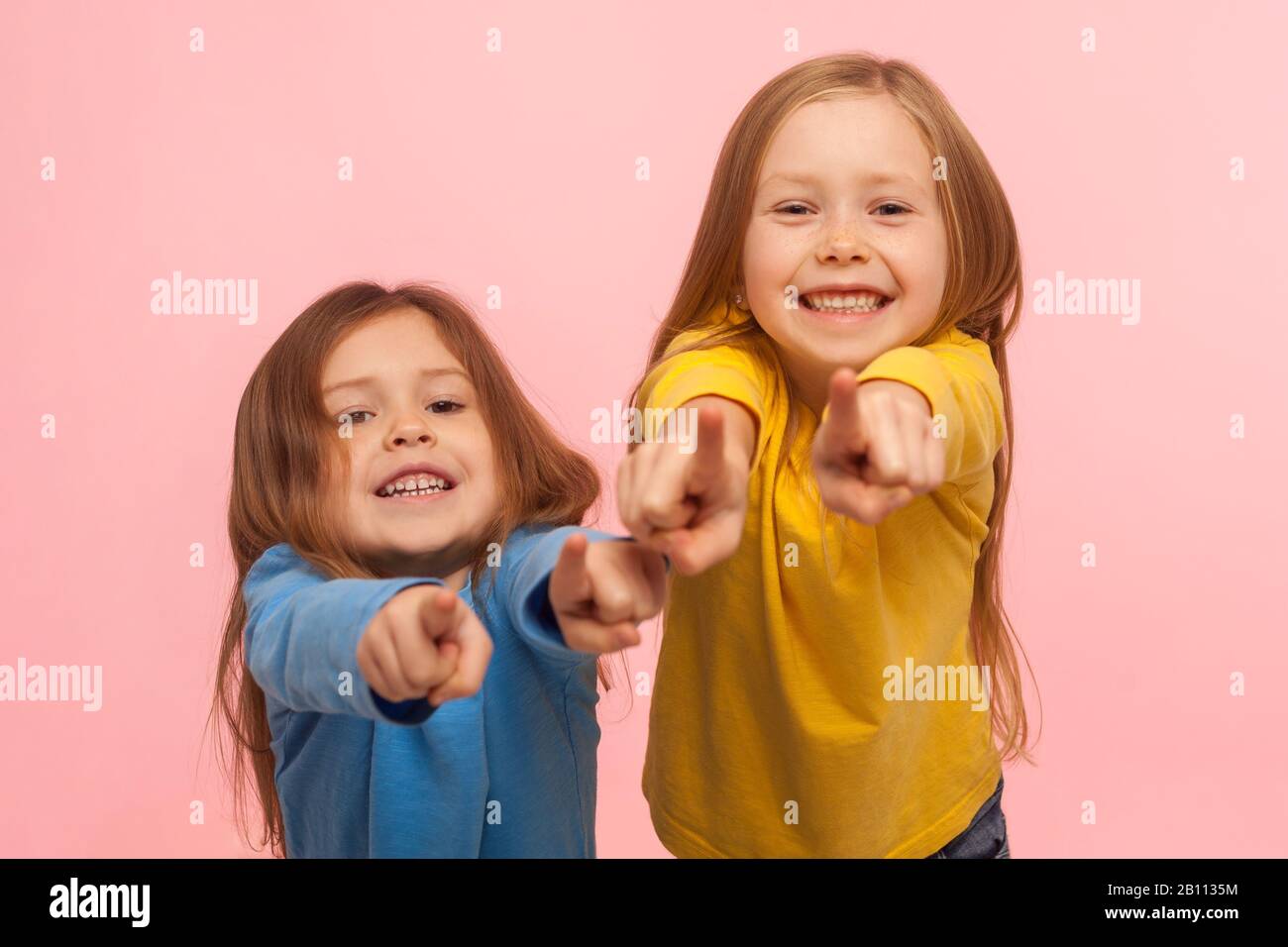Hey you! Two charming happy little girls pointing to camera, indicating ...