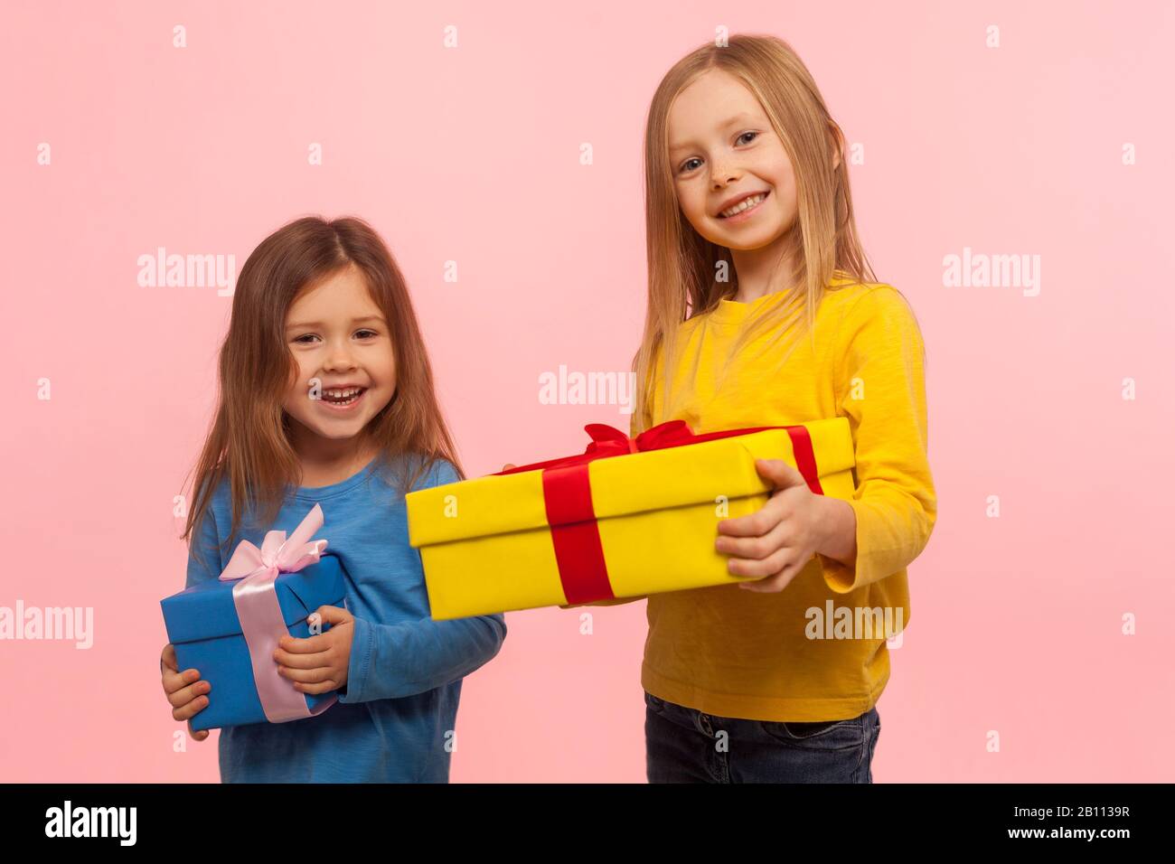 Gift for each kid. Two happy charming little girls holding wrapped ...