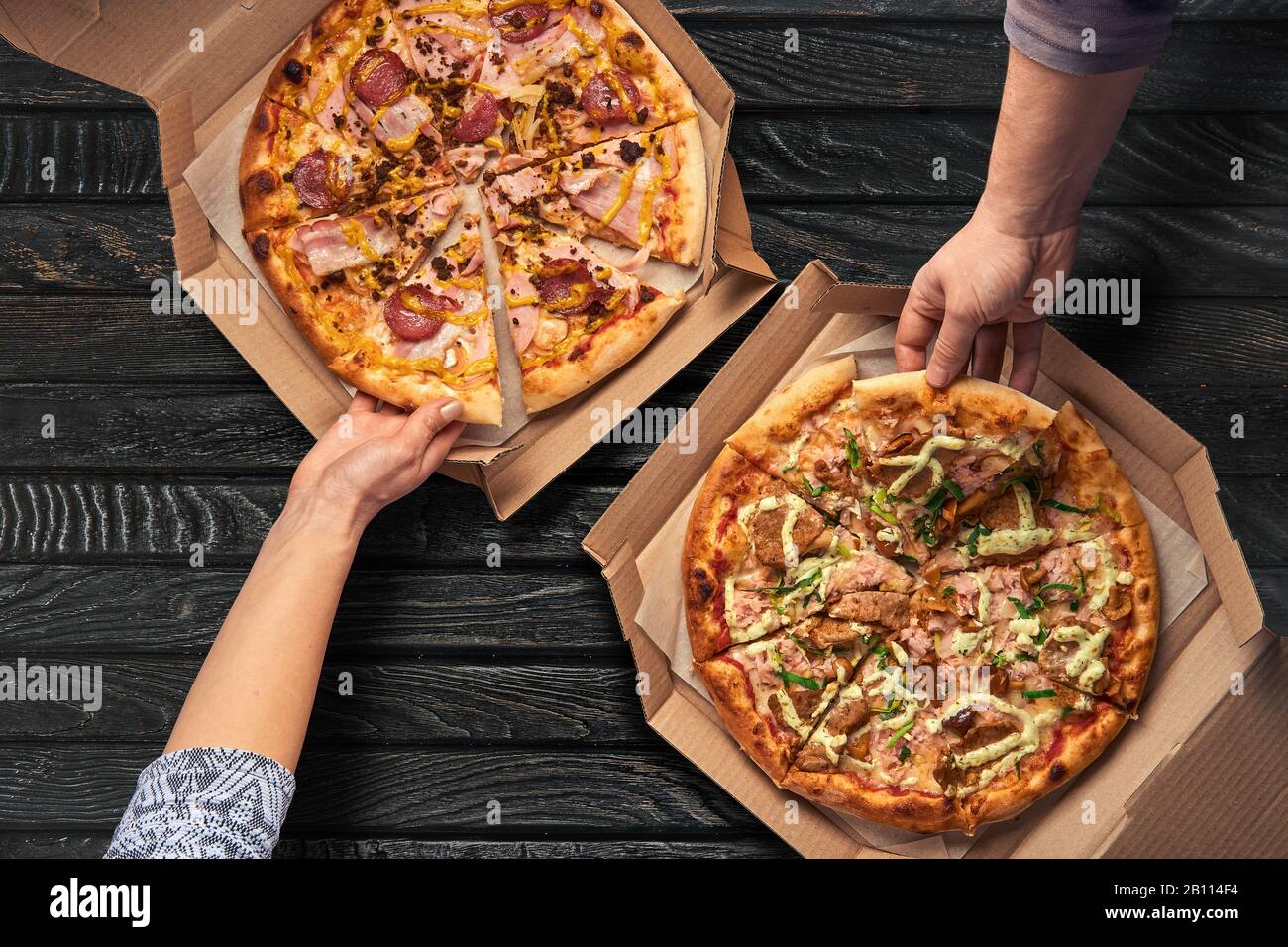 Overhead view of hands taking pizza from cardboard box Stock Photo - Alamy