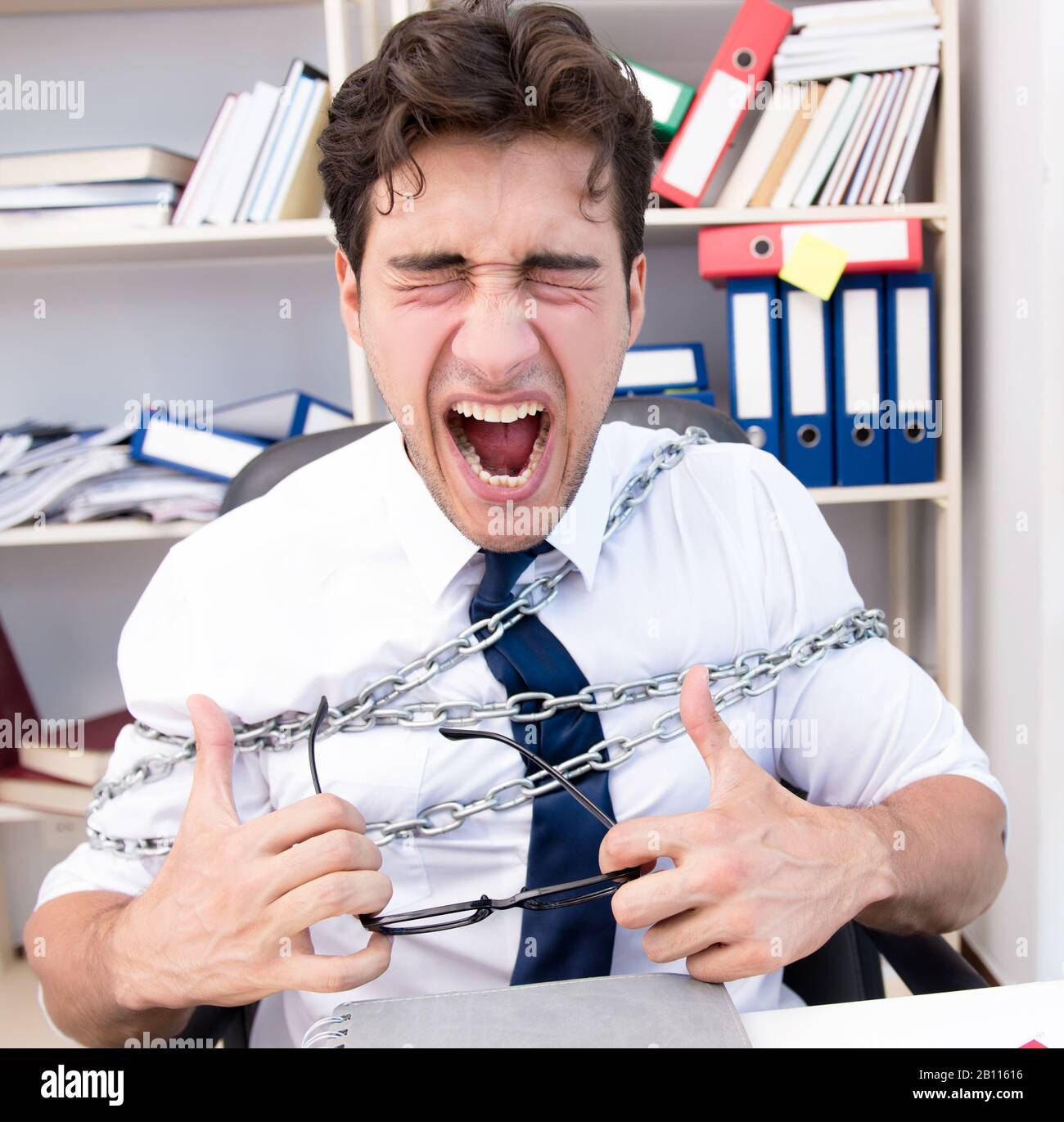 Employee attached and chained to his desk with chain Stock Photo - Alamy