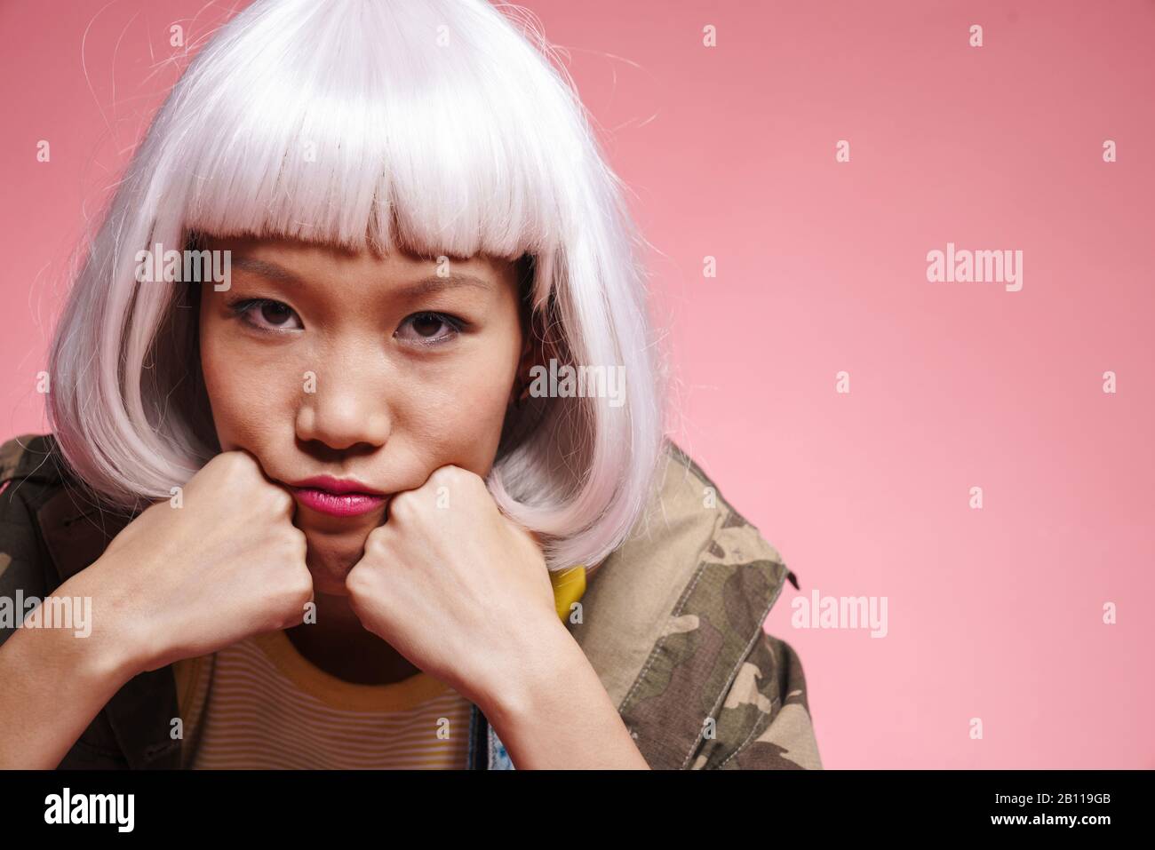 Image of displeased asian girl wearing white wig propping up her head ...