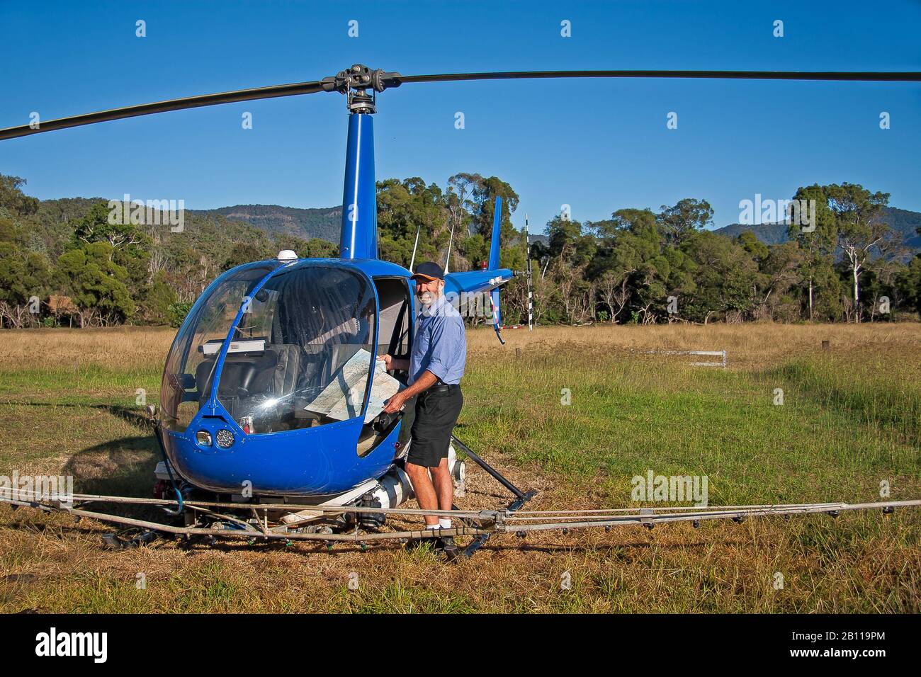 Helicopter and pilot with map get ready to fly. Agricultural work ...
