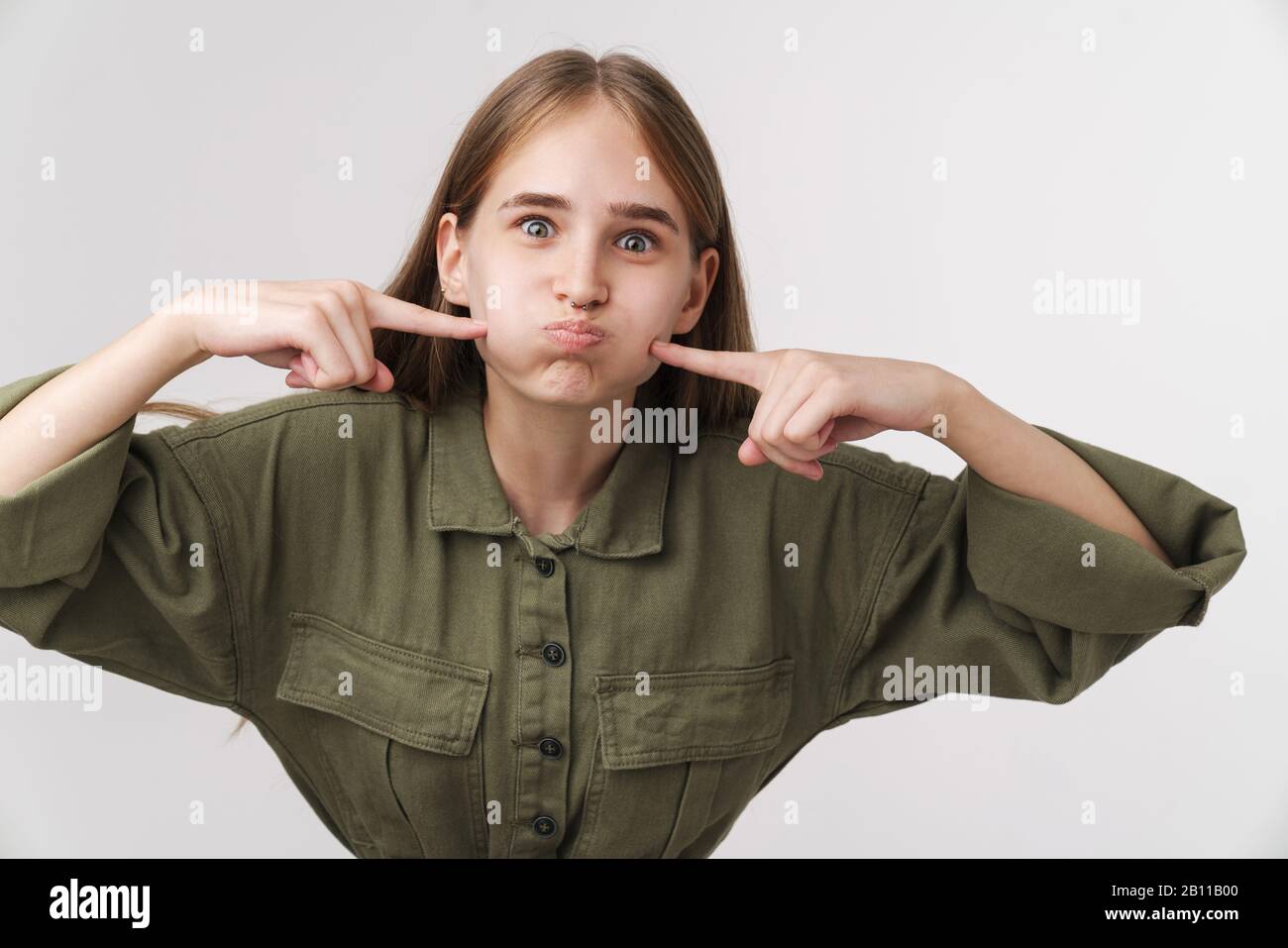 Photo of amusing caucasian woman pointing fingers at cheeks and ...