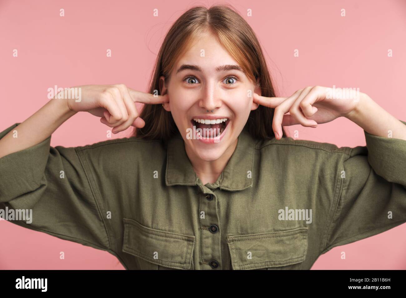 Photo of delighted caucasian woman plugging her ears and smiling ...