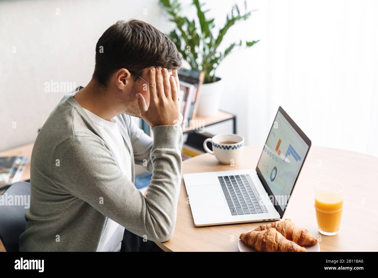 Image of serious young man in eyeglasses looking at screen while ...