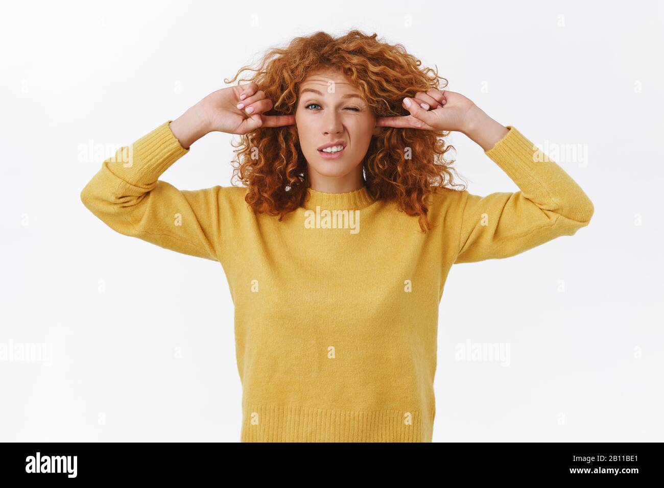 Silly displeased cute redhead curly girl shut her ears, plug fingers ...