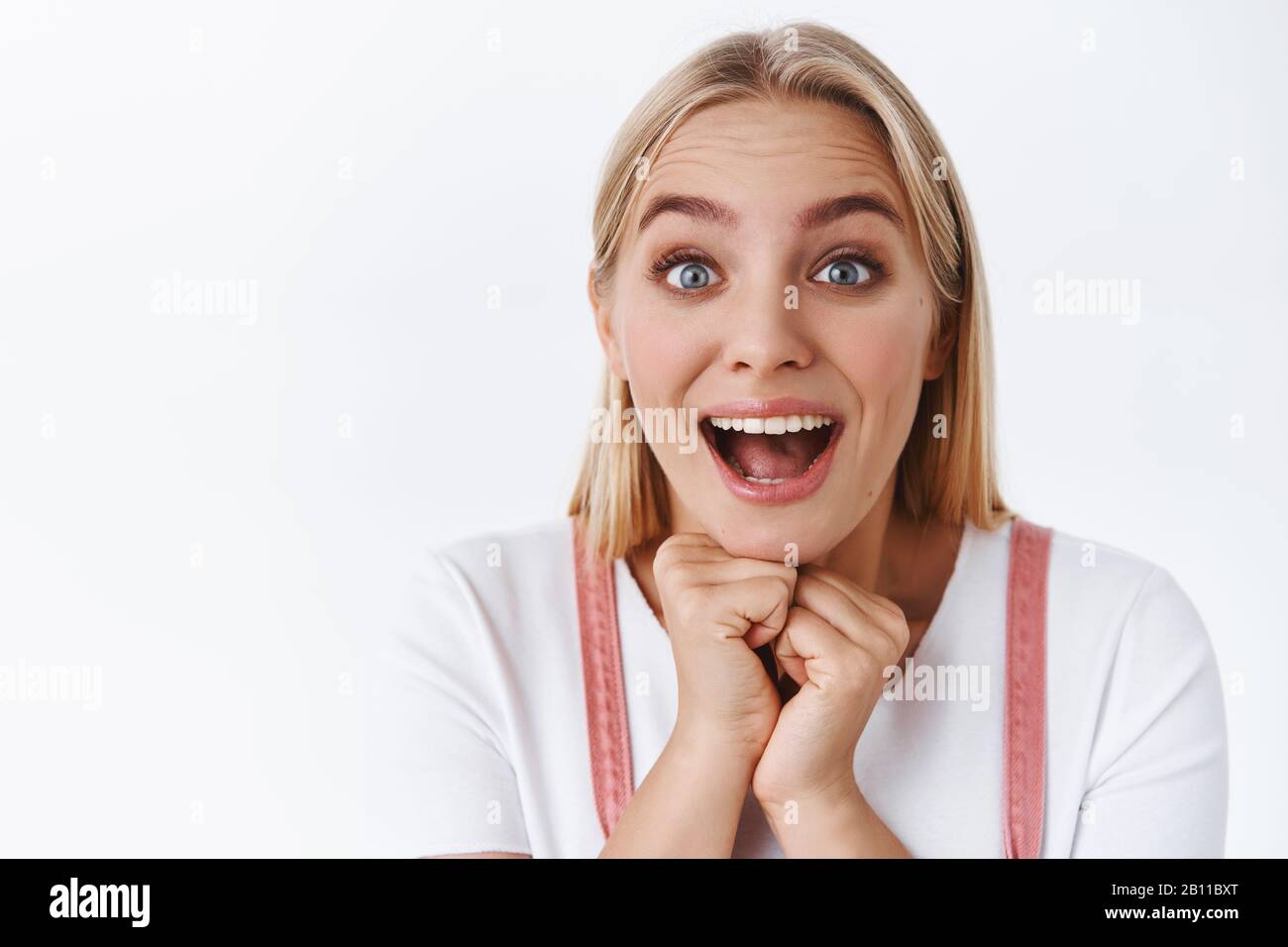 Close-up excited and amused, surprised young blond woman with blue eyes ...