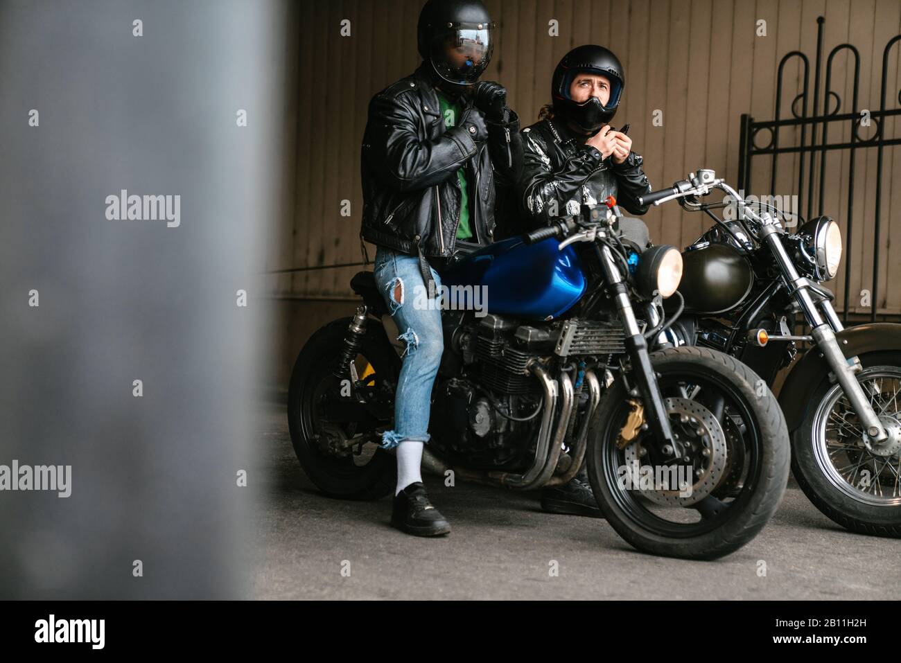 Photo of young caucasian men bikers wearing helmets talking while ...