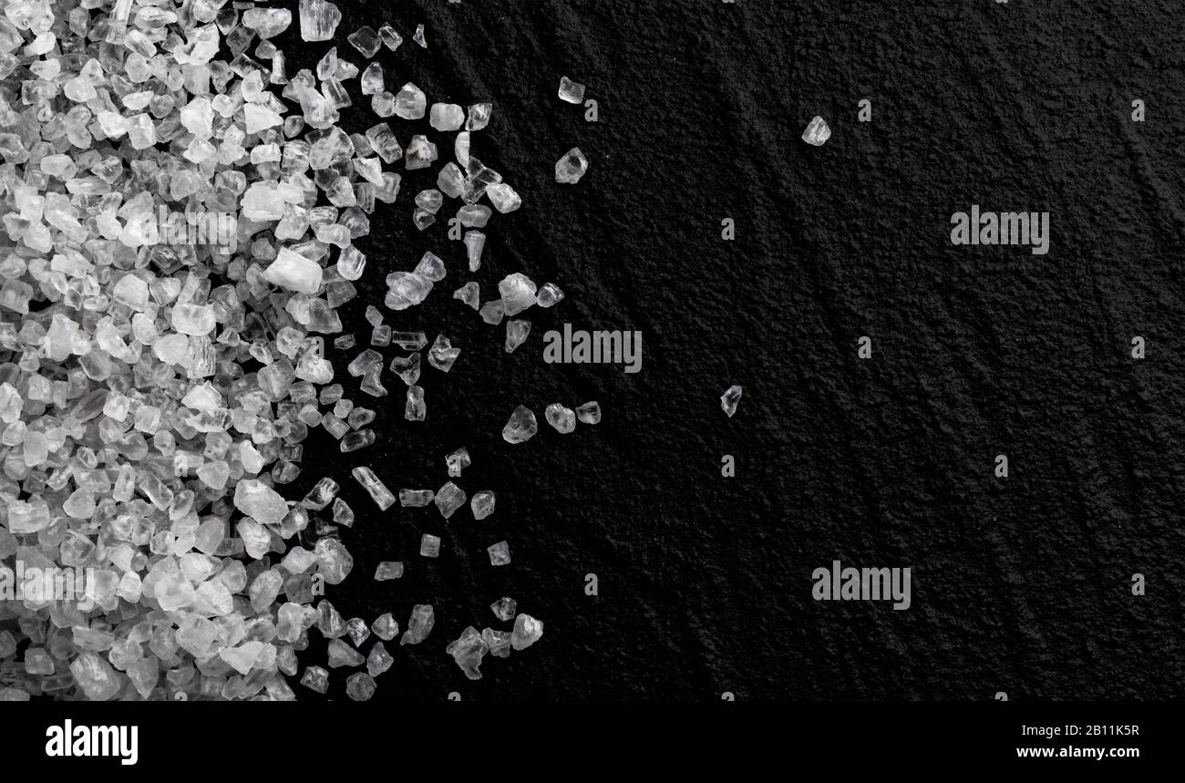 Heap of coarse sea salt on black background with copy space, top view ...