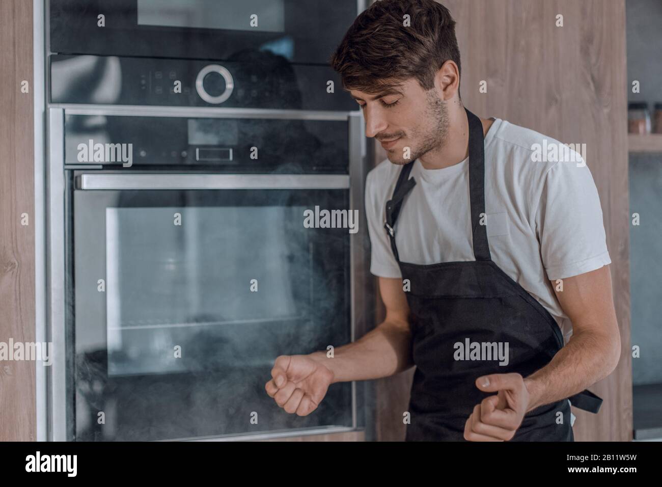 frustrated young man standing near broken oven Stock Photo - Alamy