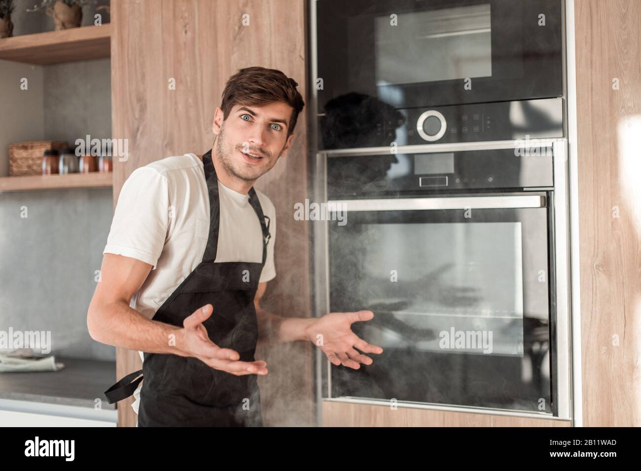 frustrated young man standing near broken oven Stock Photo - Alamy