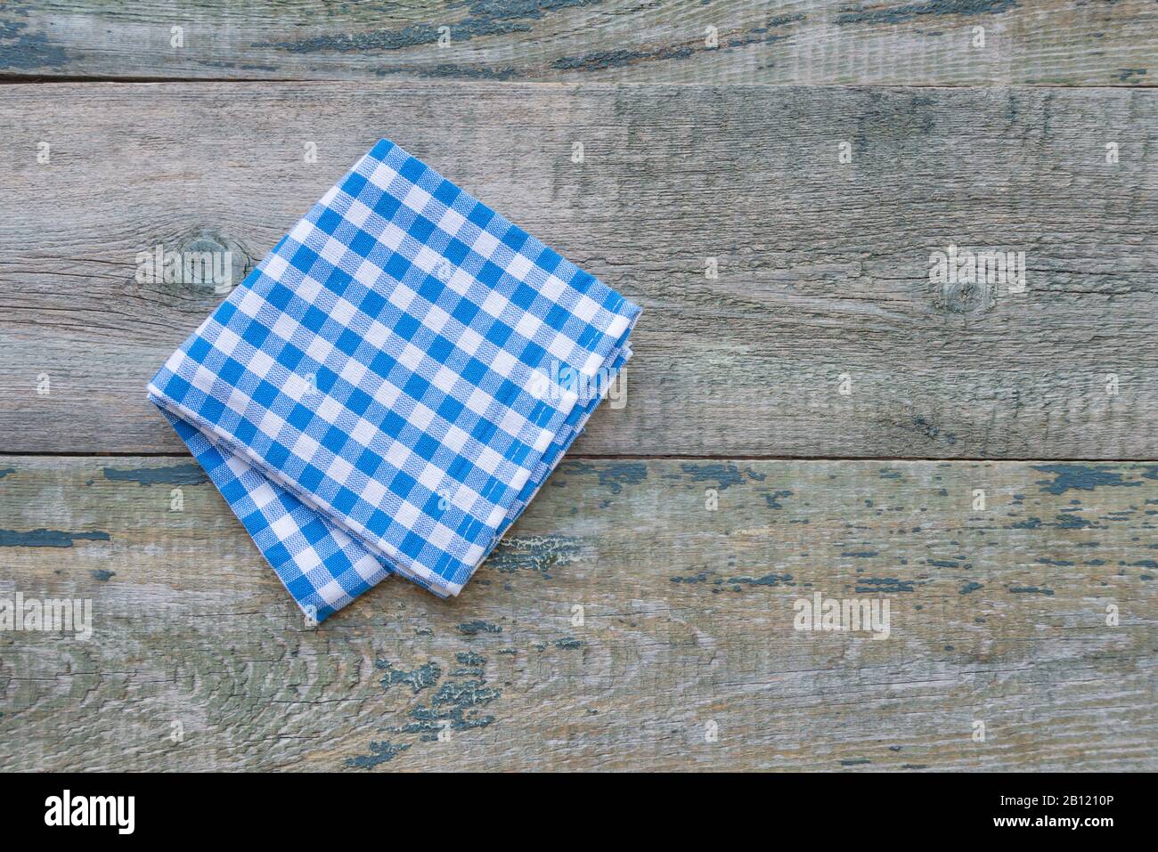 Checkered blue-and-white napkin is on a rough background of wooden ...