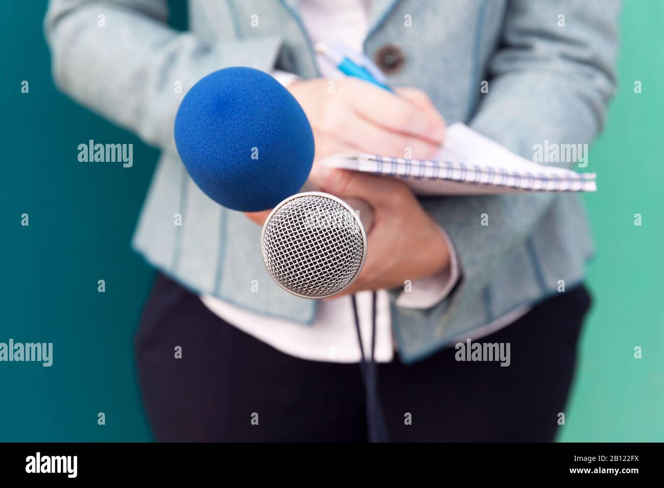 News reporter or TV journalist at press conference, holding microphone ...