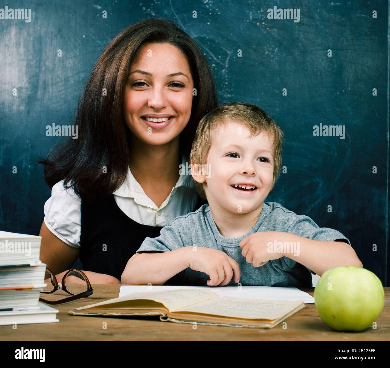 little cute boy in glasses with young real teacher, classroom studying ...