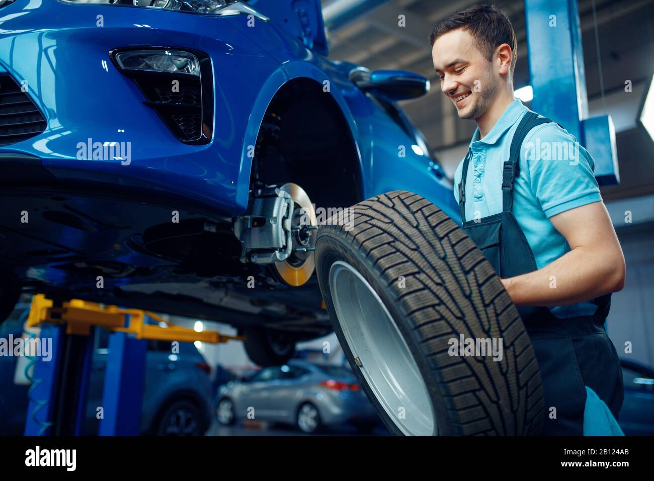 Worker removes wheel from vehicle, car service Stock Photo - Alamy