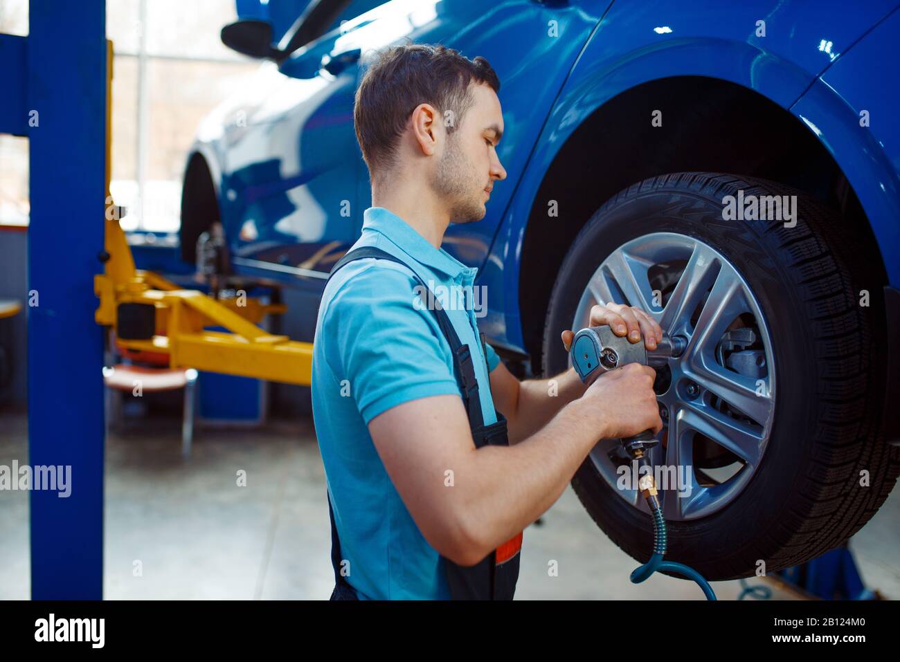 Worker removes wheel from vehicle on lift Stock Photo - Alamy
