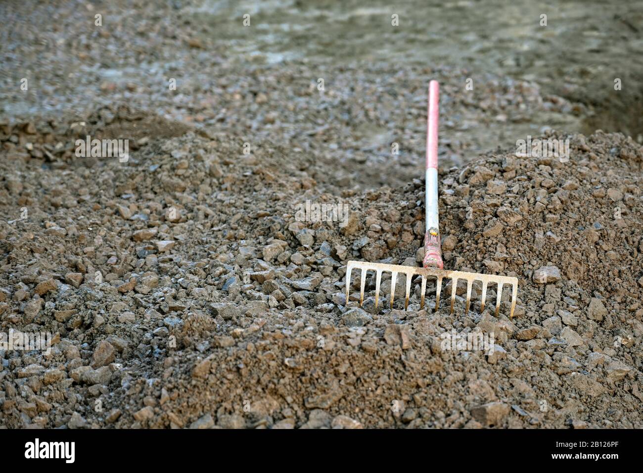 Metal rake lying on a pile of gravel on a building site Stock Photo - Alamy