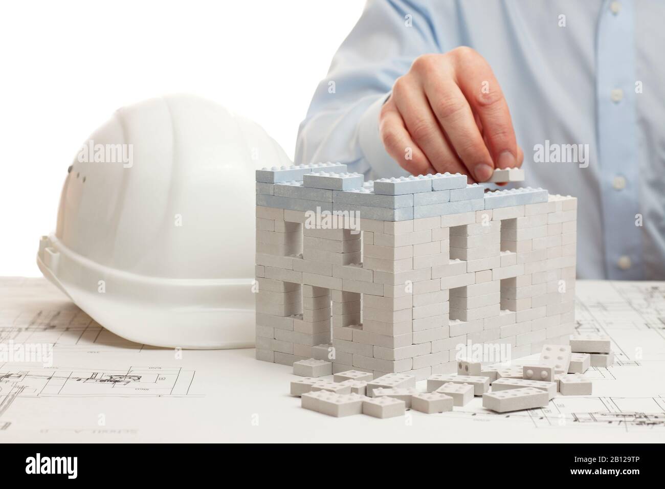 Hand of an architect constructing a house with toy blocks - white ...