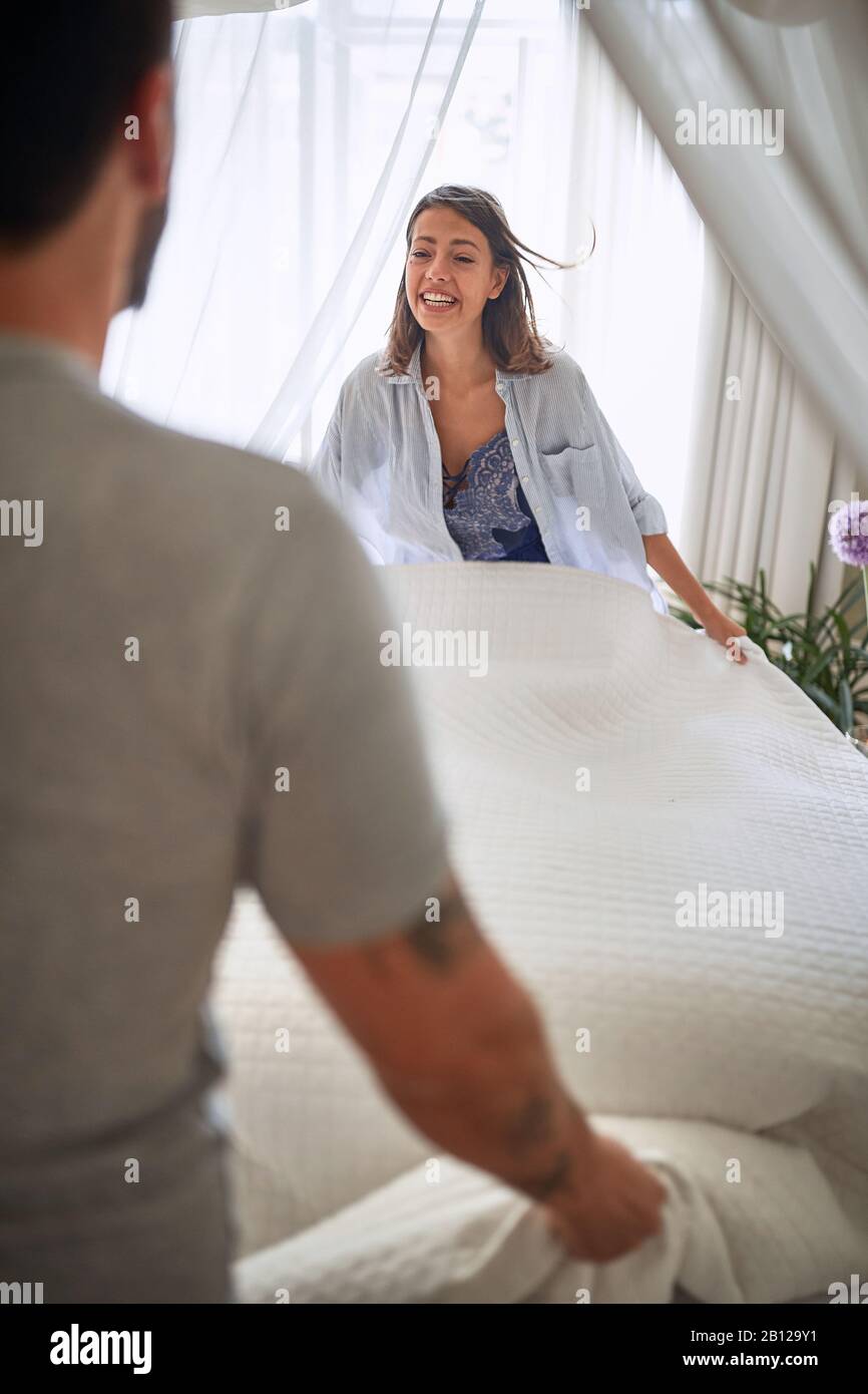 young couple spreading sheets in the bedroom with joy, smiling. bedroom ...