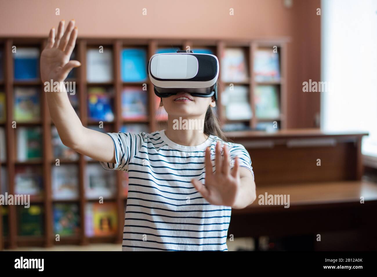 Contemporary teenage girl with vr headset touching virtual display ...