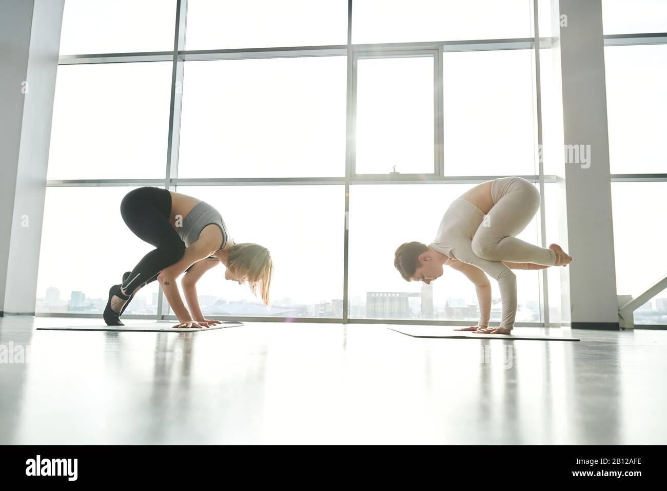 Two young active women in sportswear standing on hands while practicing ...