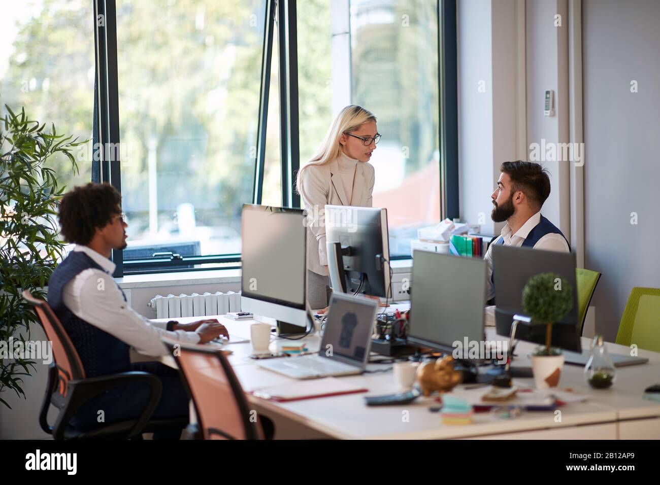 blonde female boss talking to employees at the modern bright office ...
