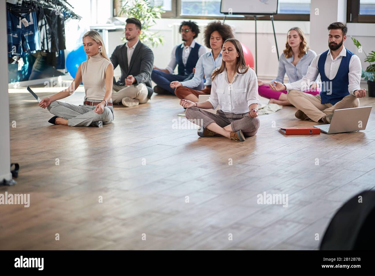 business colleagues meditating at work, sitting on the floor; copy ...