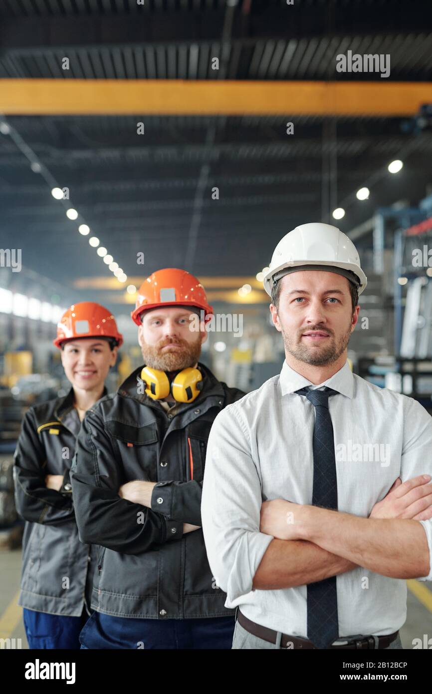 Young confident cross-armed leader of engineering team and his trainees ...