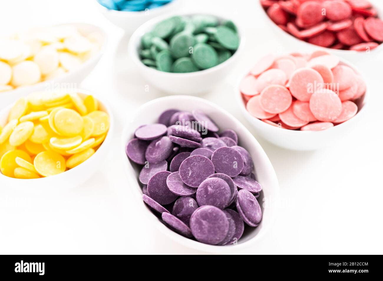 Rainbow colors of round chocolate chips in a white bowls for melting ...
